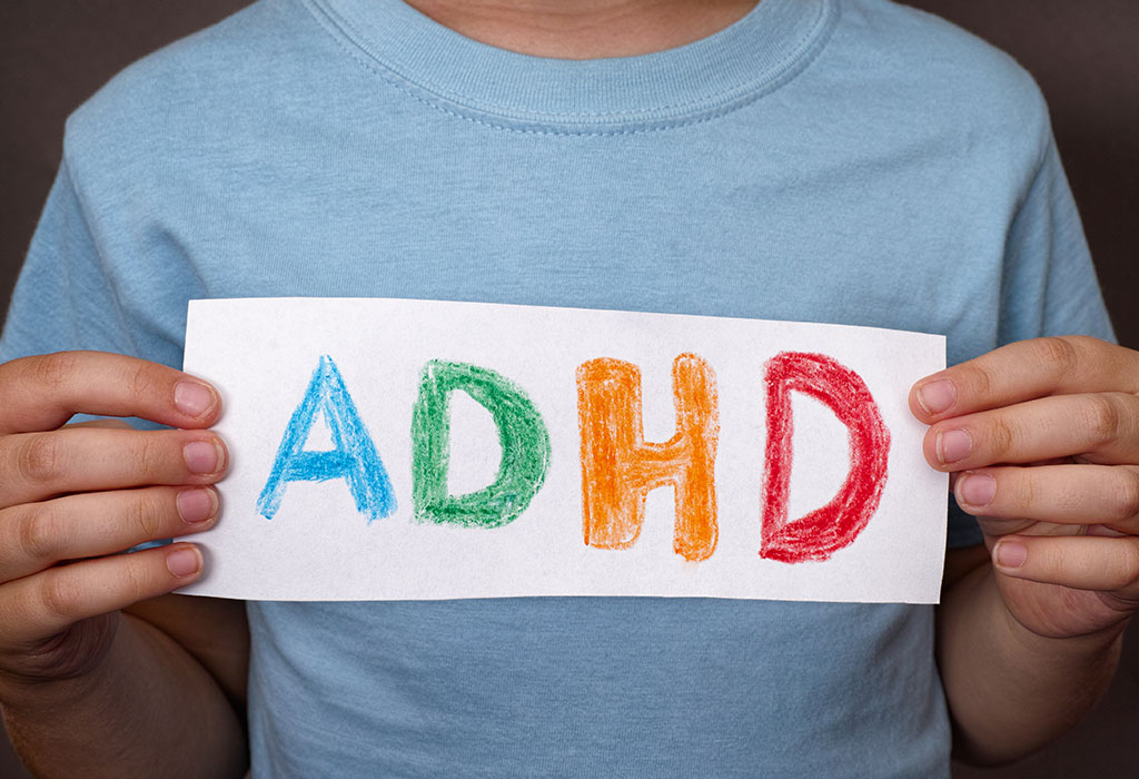 A Little Boy Holding A Piece Of Paper With ADHD Written On It